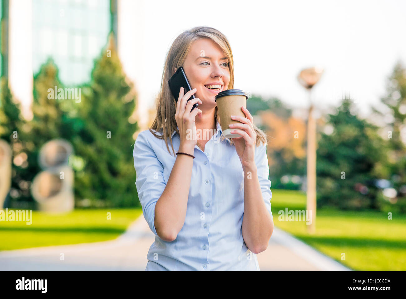Beautiful woman texting on a smart phone in a park with a green ...