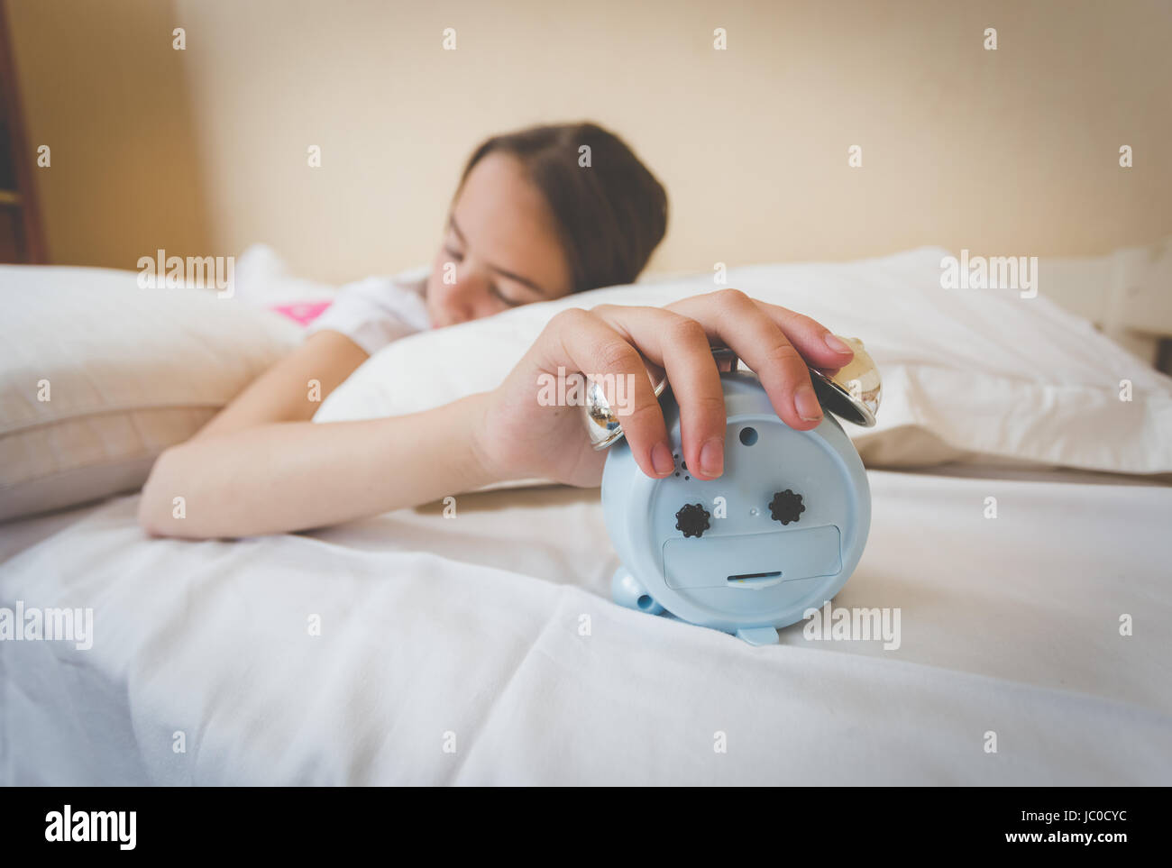 Closeup photo of young woman turning off alarm clock Stock Photo - Alamy