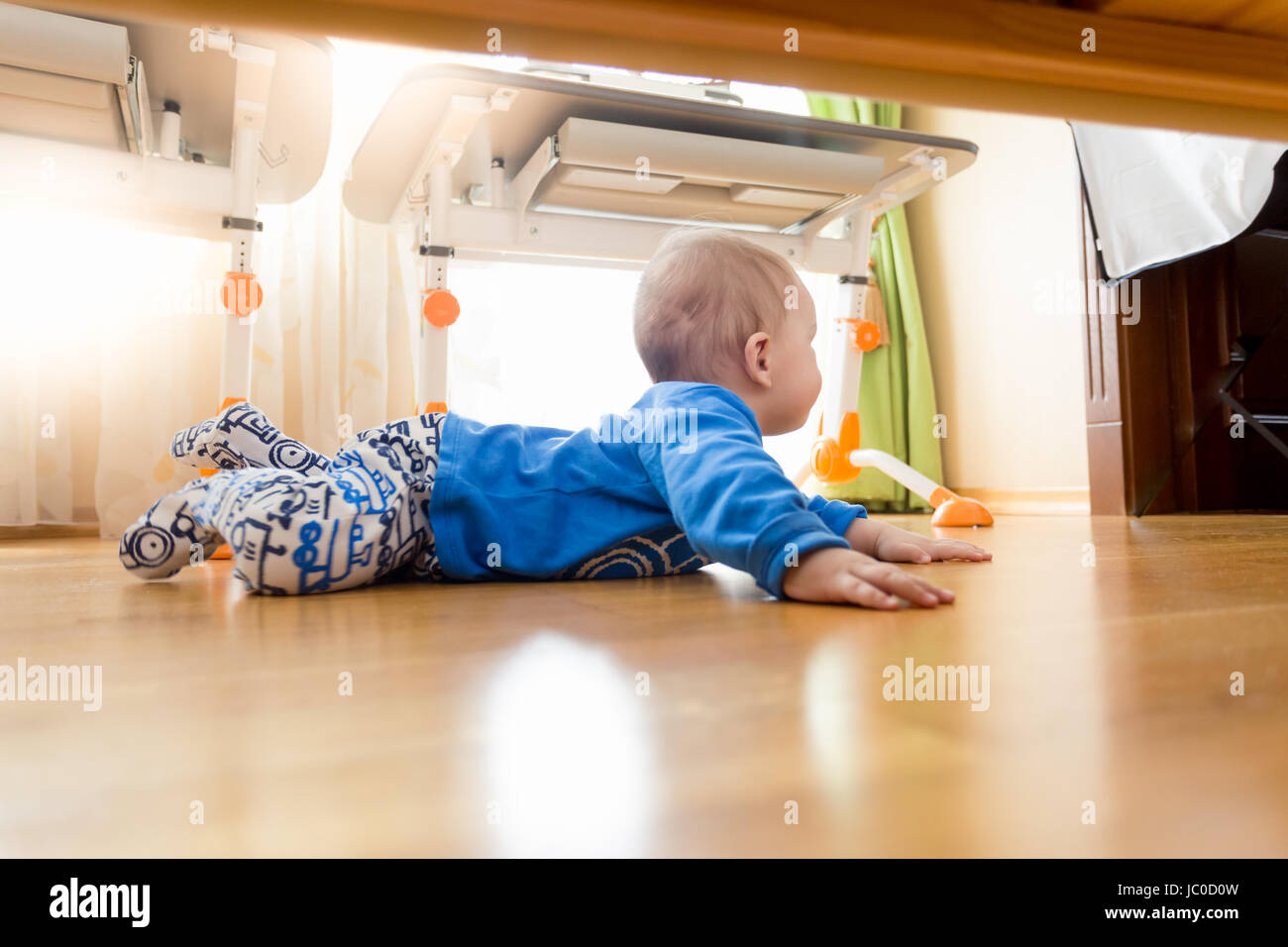 View from under the bed on cute baby crawling on floor at bedroom Stock ...