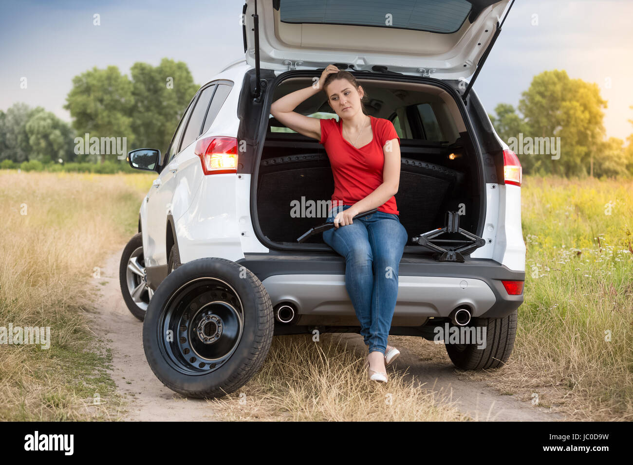 Young sad woman sitting in broken car at field Stock Photo - Alamy