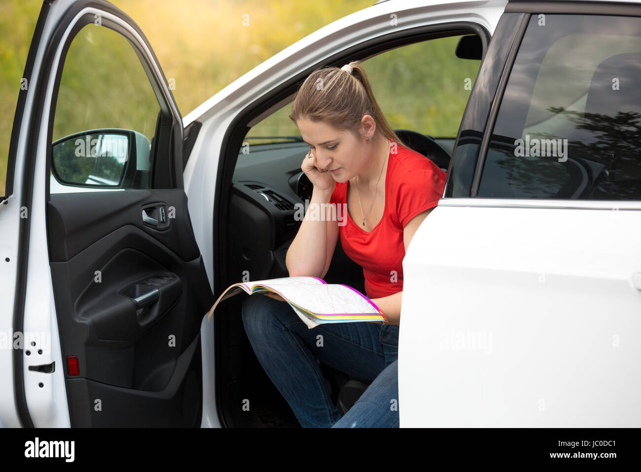 Young female driver got lost while driving in countryside and reading ...