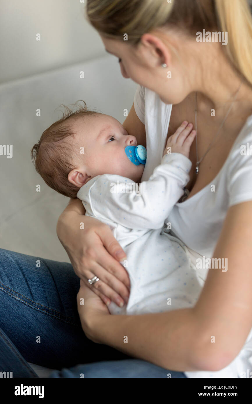 Beautiful young mother rocking her cute baby on hands Stock Photo - Alamy