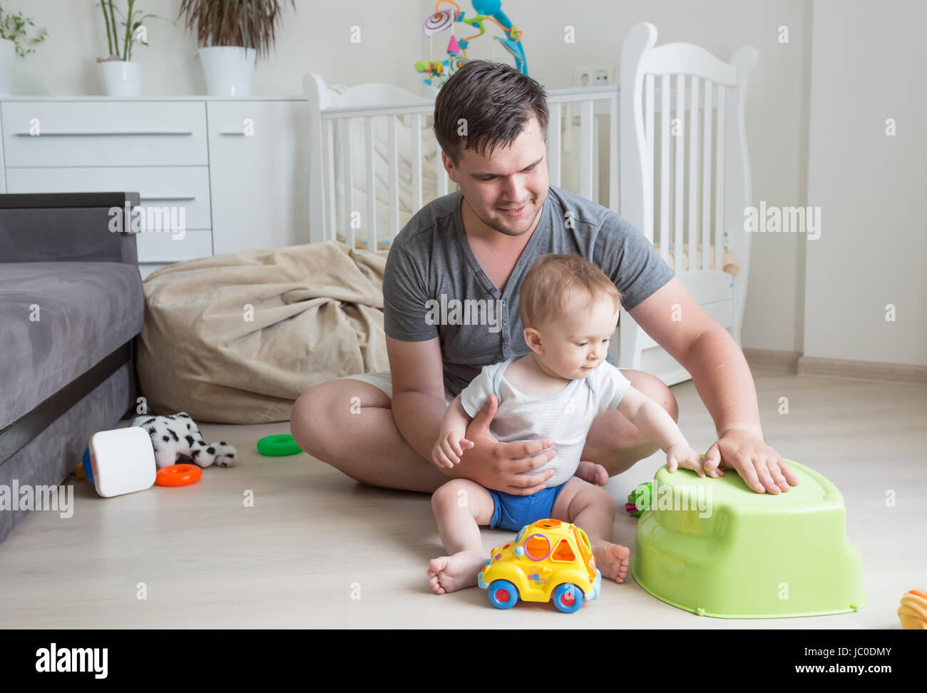 Cheerful father having fun with his baby boy and playing on floor at ...
