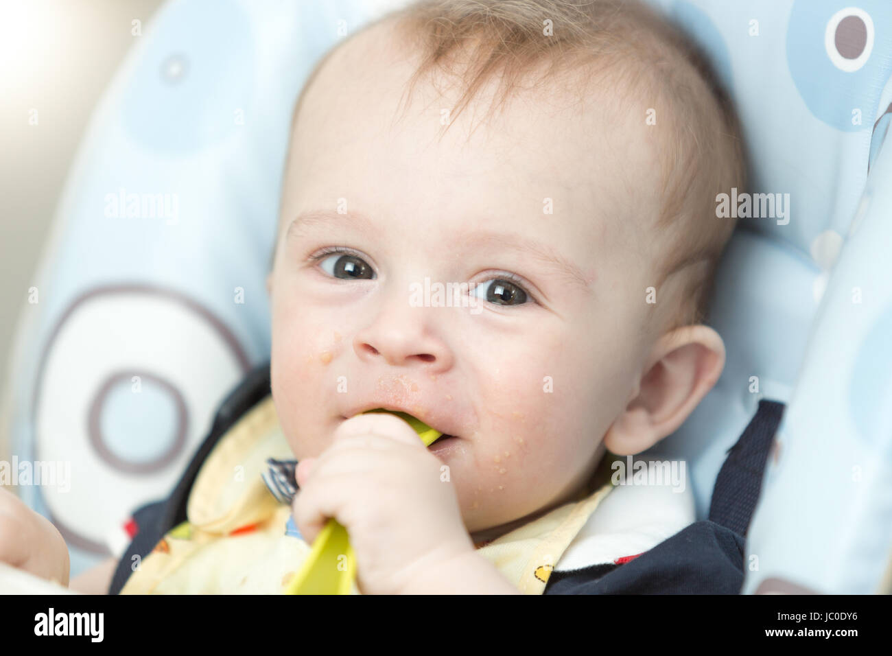 Closeup portrait of happy smiling baby eating in highchair at kitchen ...