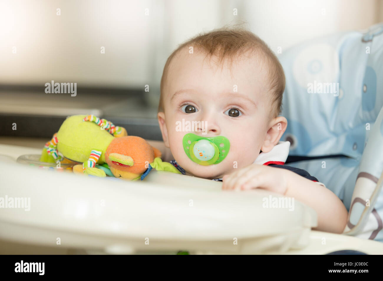 Closeup portrait of cute baby boy with soother waiting for breakfast in ...