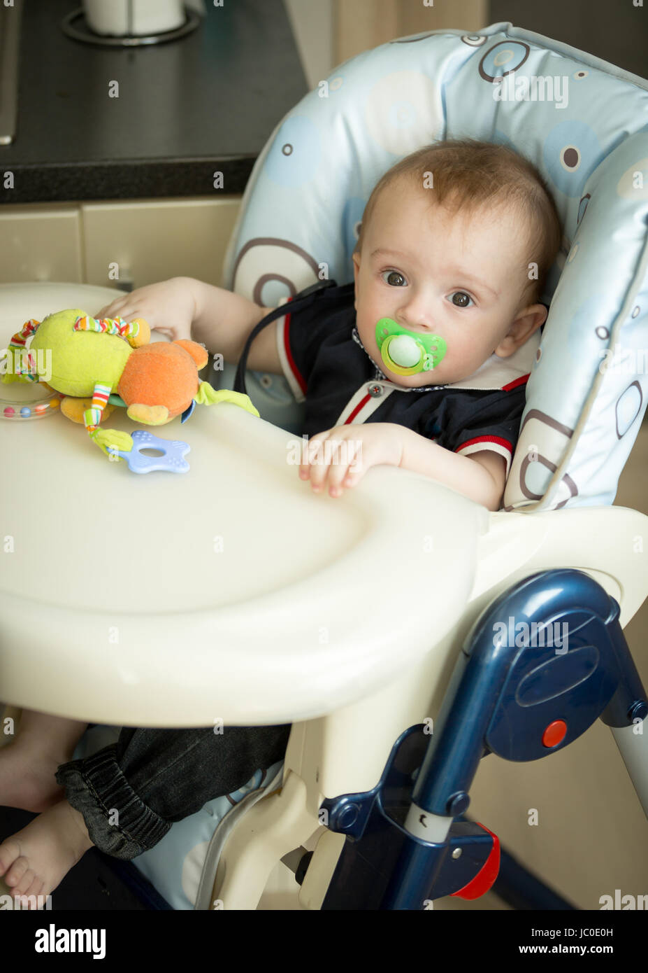 Cute baby boy with soother sitting in chair for feeding Stock Photo - Alamy