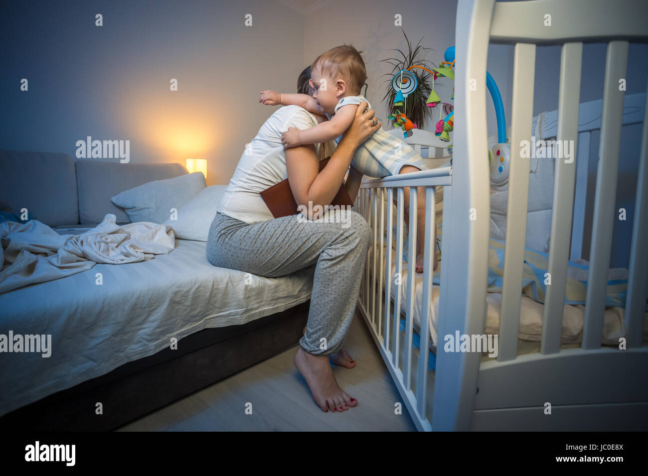 Cute baby boy got scared at night at hugging young caring mother Stock ...