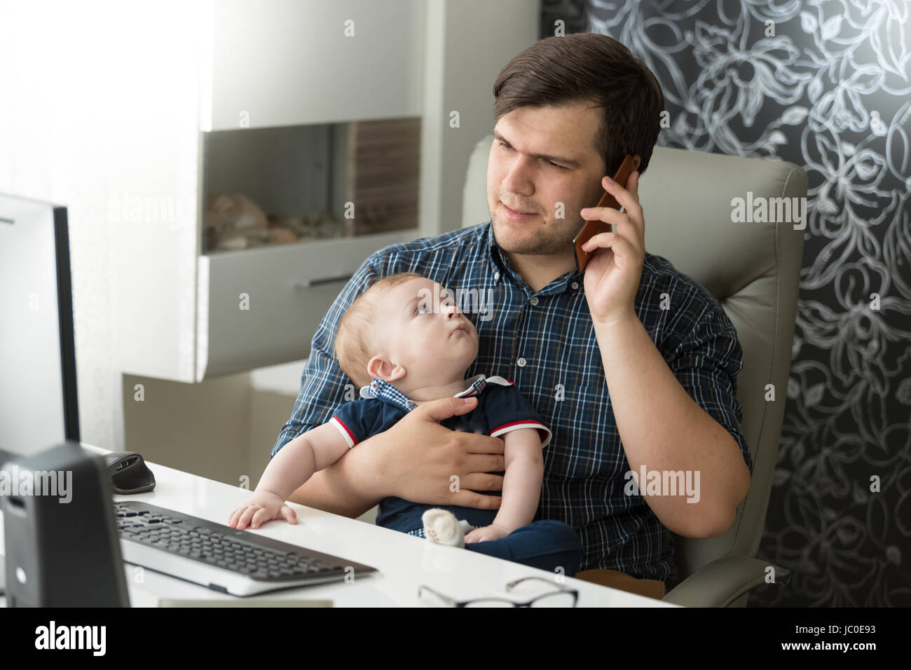 Portrait of father talking by phone and taking care of his baby Stock ...