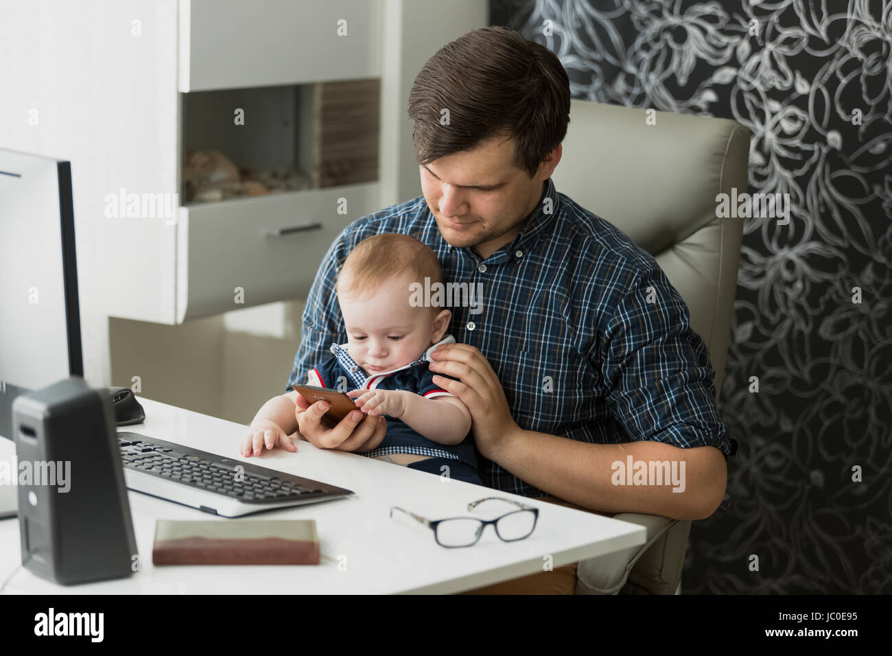 Young father working from home and taking care of his baby son Stock ...
