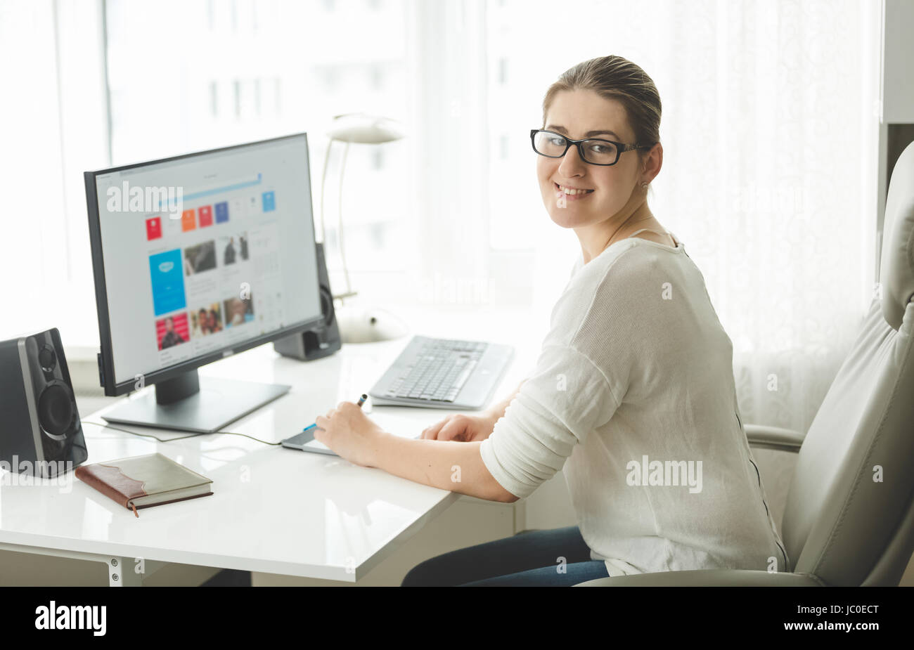 Portrait of beautiful smiling woman working at computer in home office ...