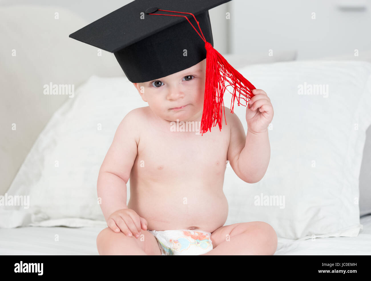 Closeup portrait of adorable baby boy in black graduation cap with red ...