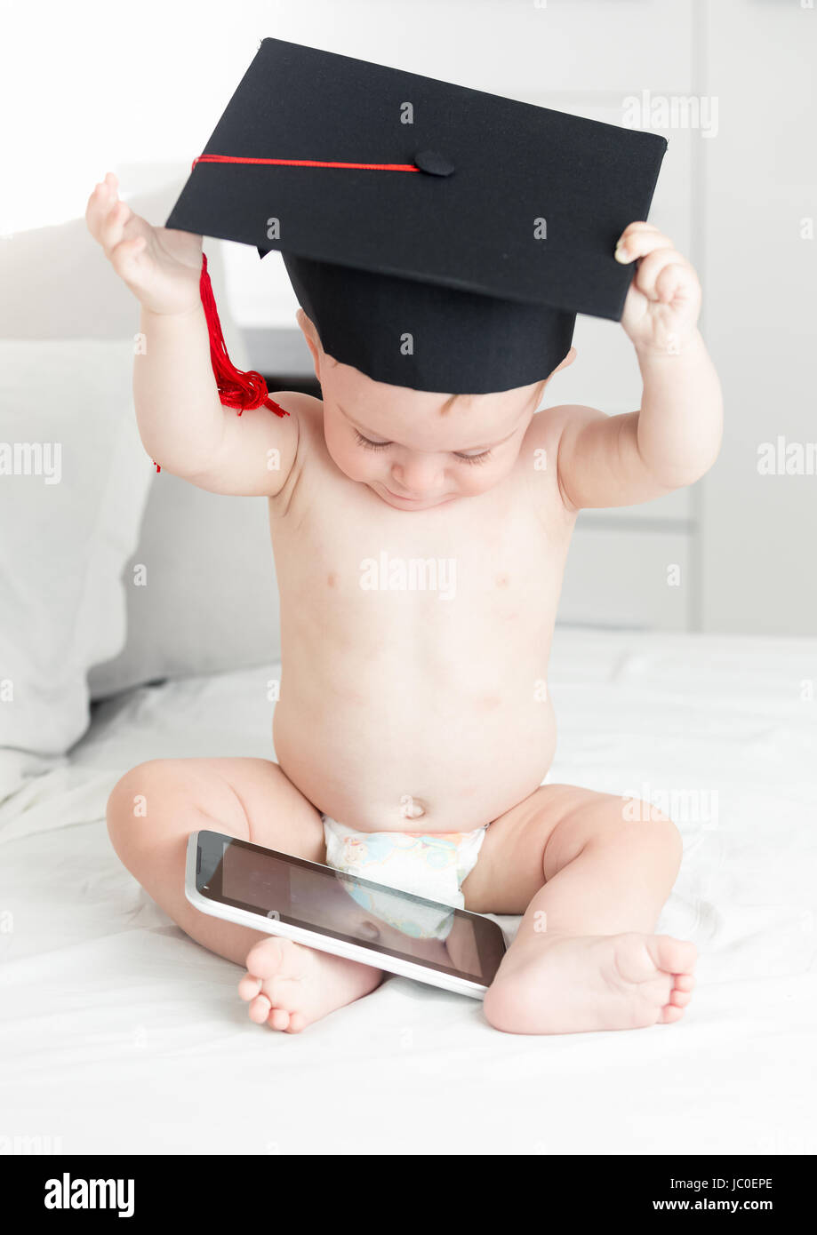 Concept of smart baby. Cute baby boy in graduation cap browsing ...