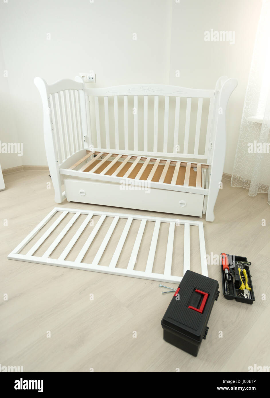 Tools box lying on floor next to disassembled wooden baby bed Stock ...