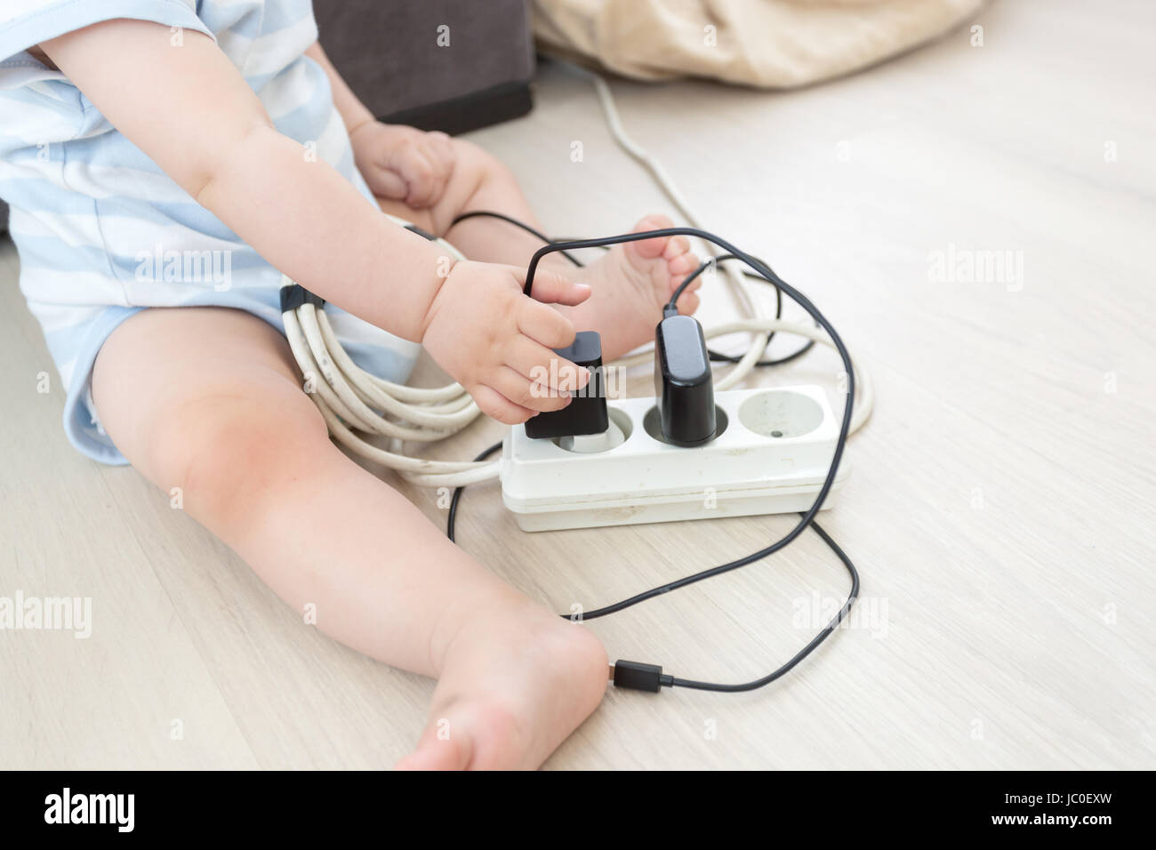 Closeup photo of baby boy pulling out cables from electrical extension ...