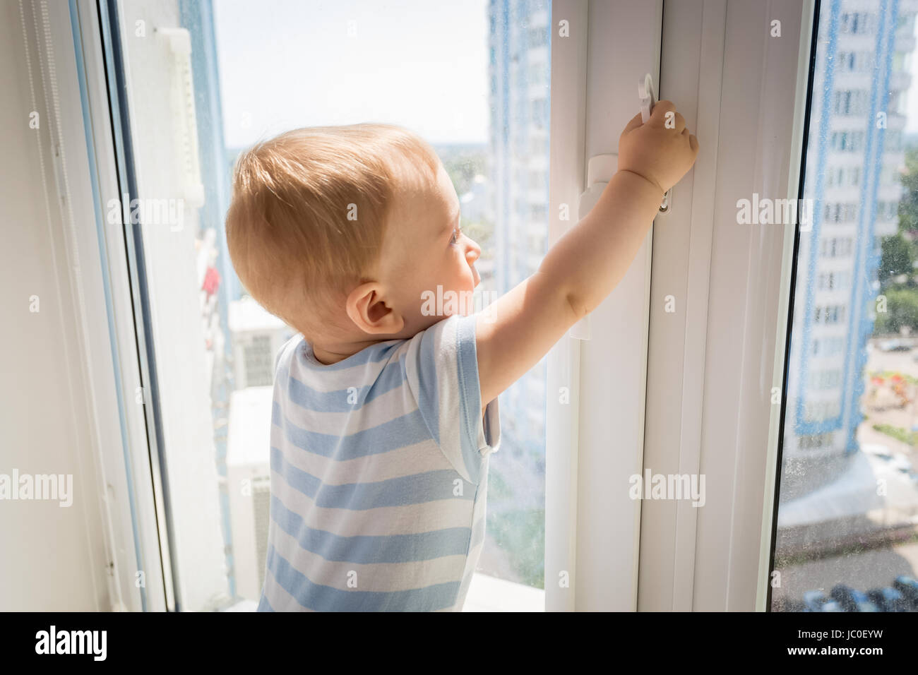 Baby in danger. Little baby trying to open window and pulling its ...