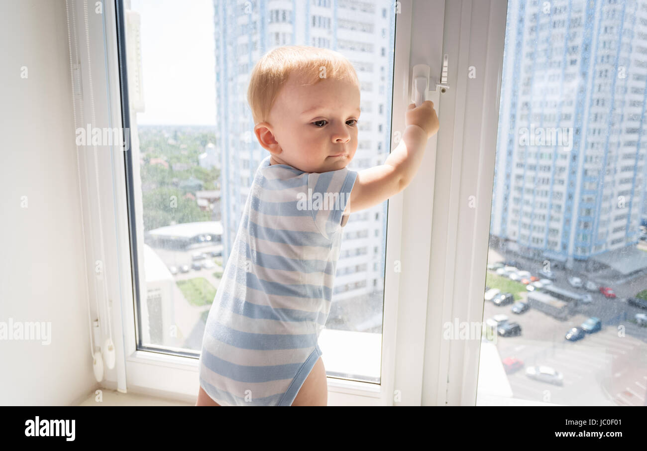 Portrait of 10 months old baby boy trying to open window Stock Photo ...