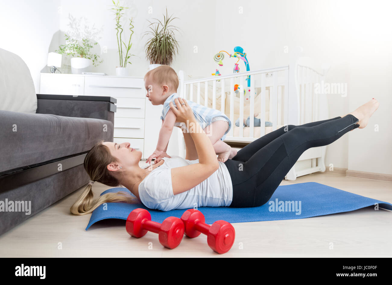Beautiful mother with her baby doing physical exercises on fitness mat ...
