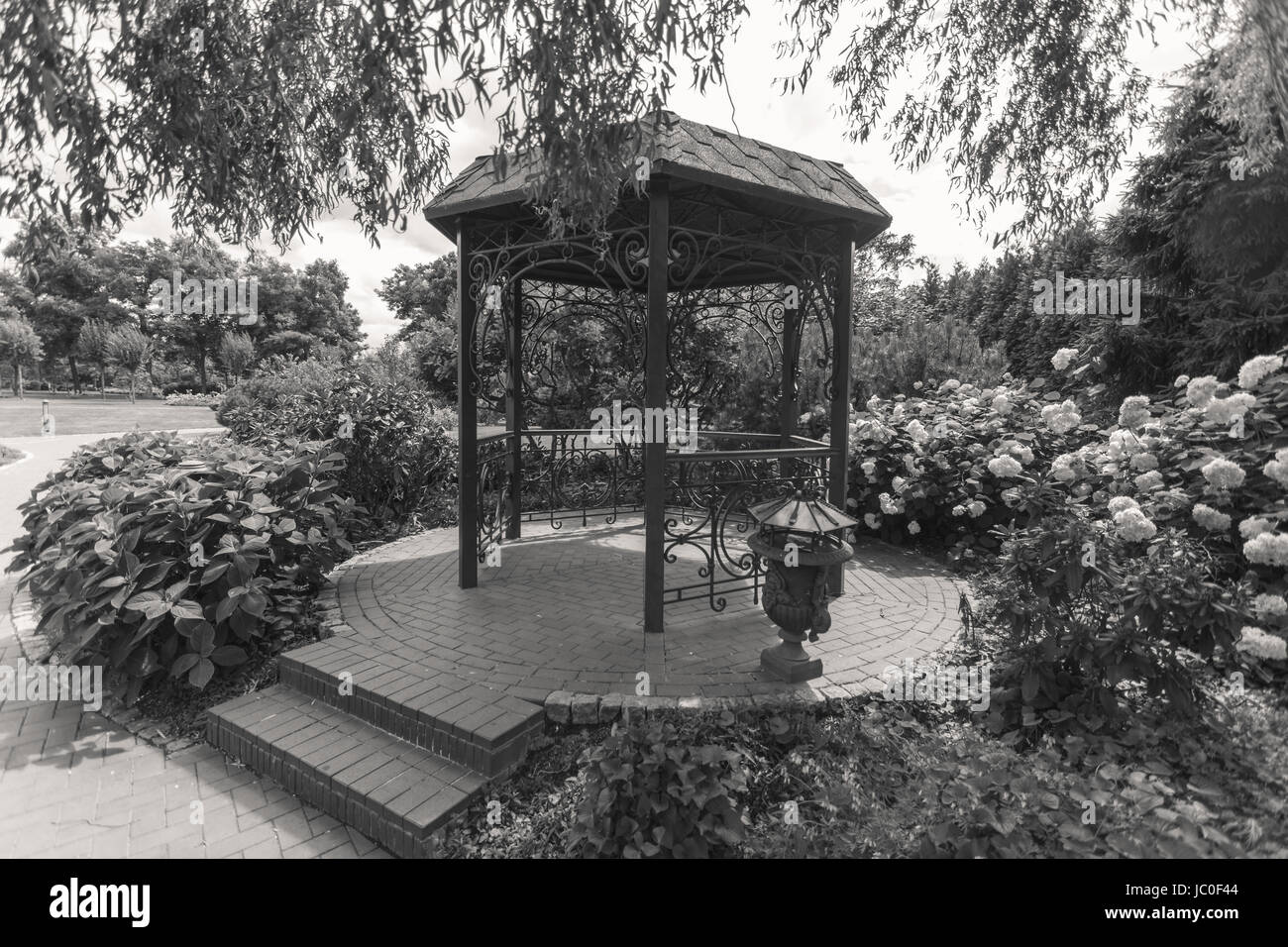 Black and white image of old metal alcove under big tree at park Stock ...