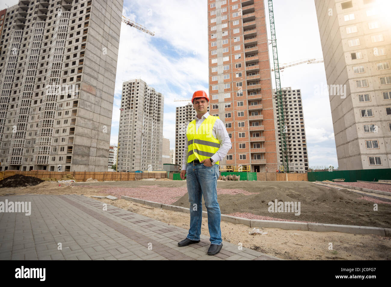 Young man in hardhat and safety vest standing on building site Stock ...