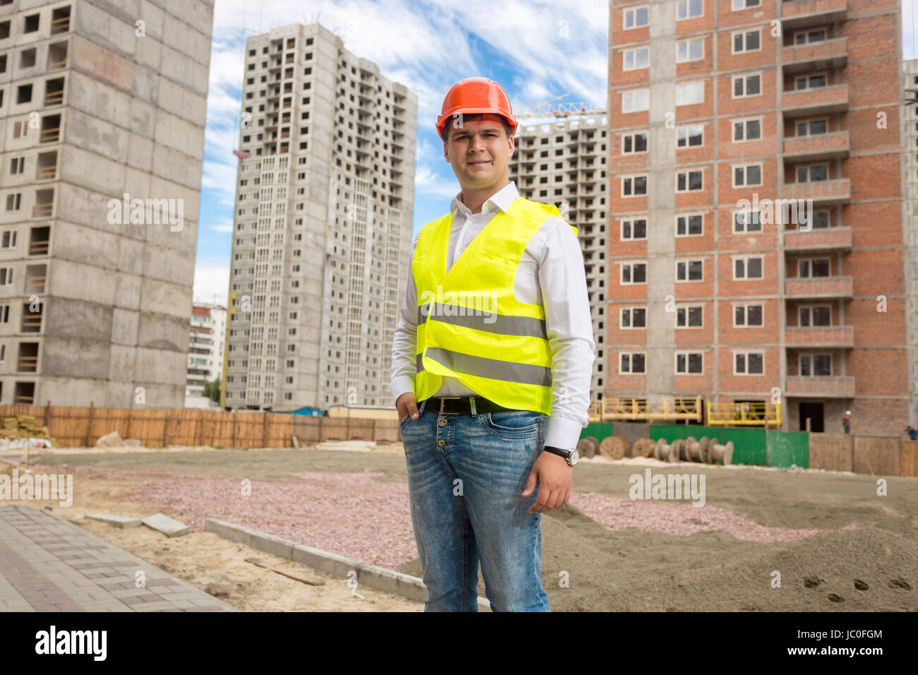 Portrait of smiling young architect standing at buildings under ...