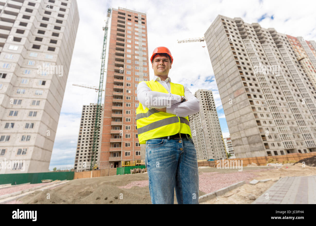 Portrait of handsome construction engineer standing on building site ...
