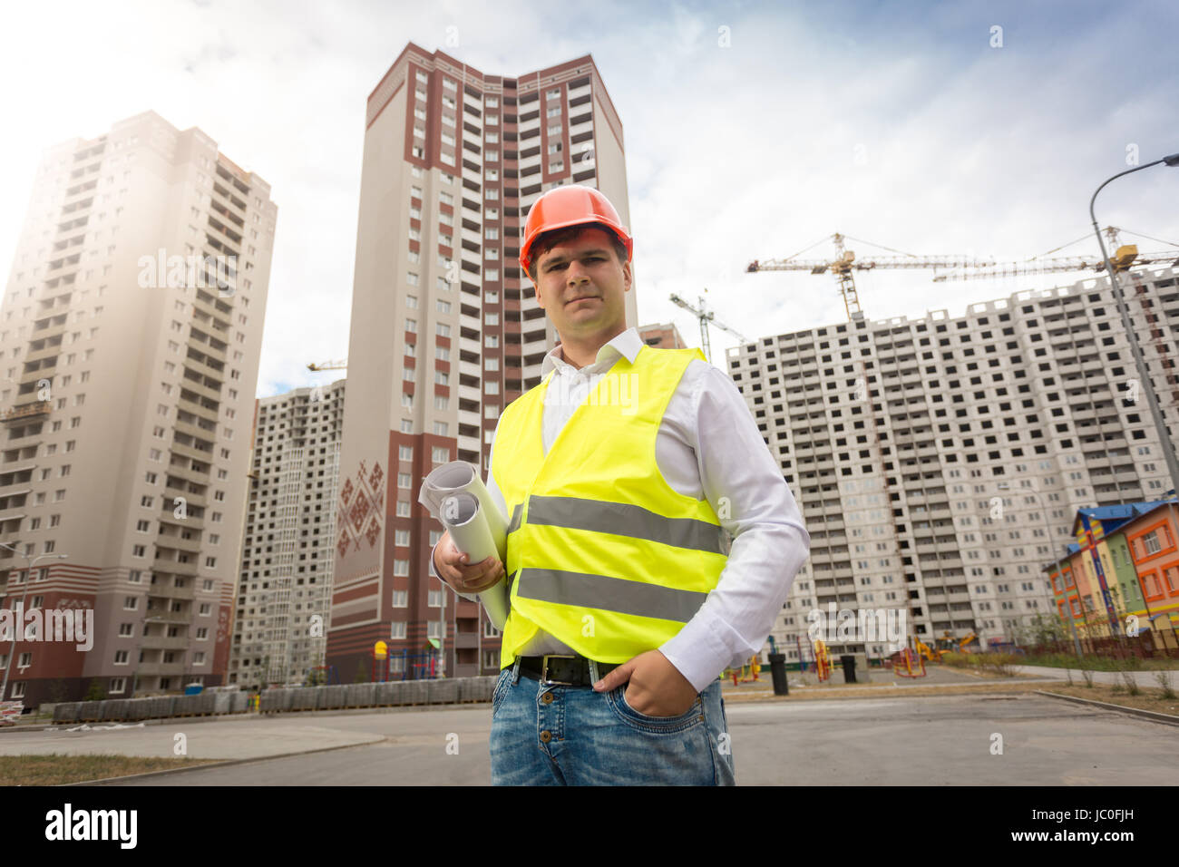 Portrait of young smiling engineer standing on building site Stock ...