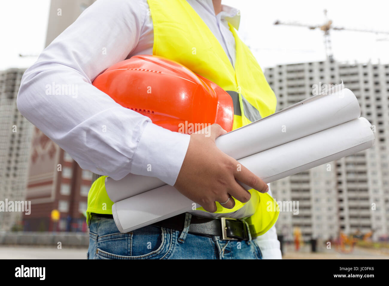 Closeup image of construction engineer holding blueprints and orange ...
