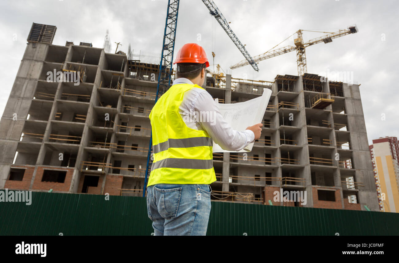 Young engineer on building site checking plans and blueprints Stock ...