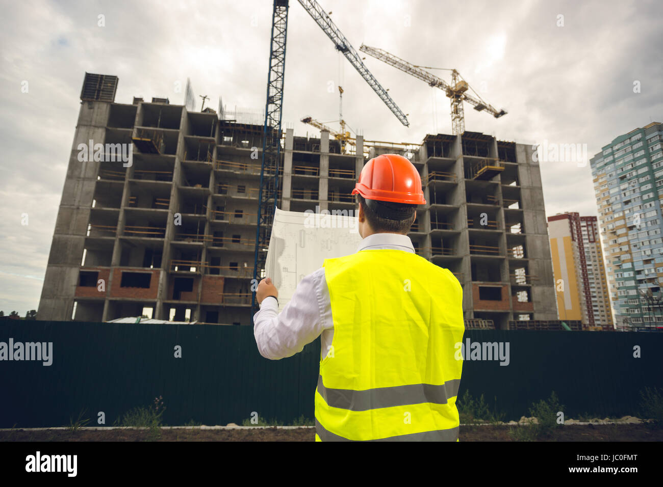 Toned image of young construction engineer reading blueprints at ...