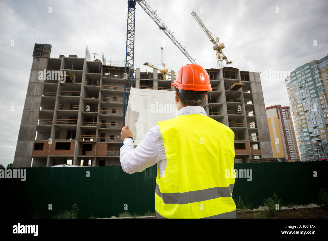 Rear view of construction engineer looking at plan of building Stock ...