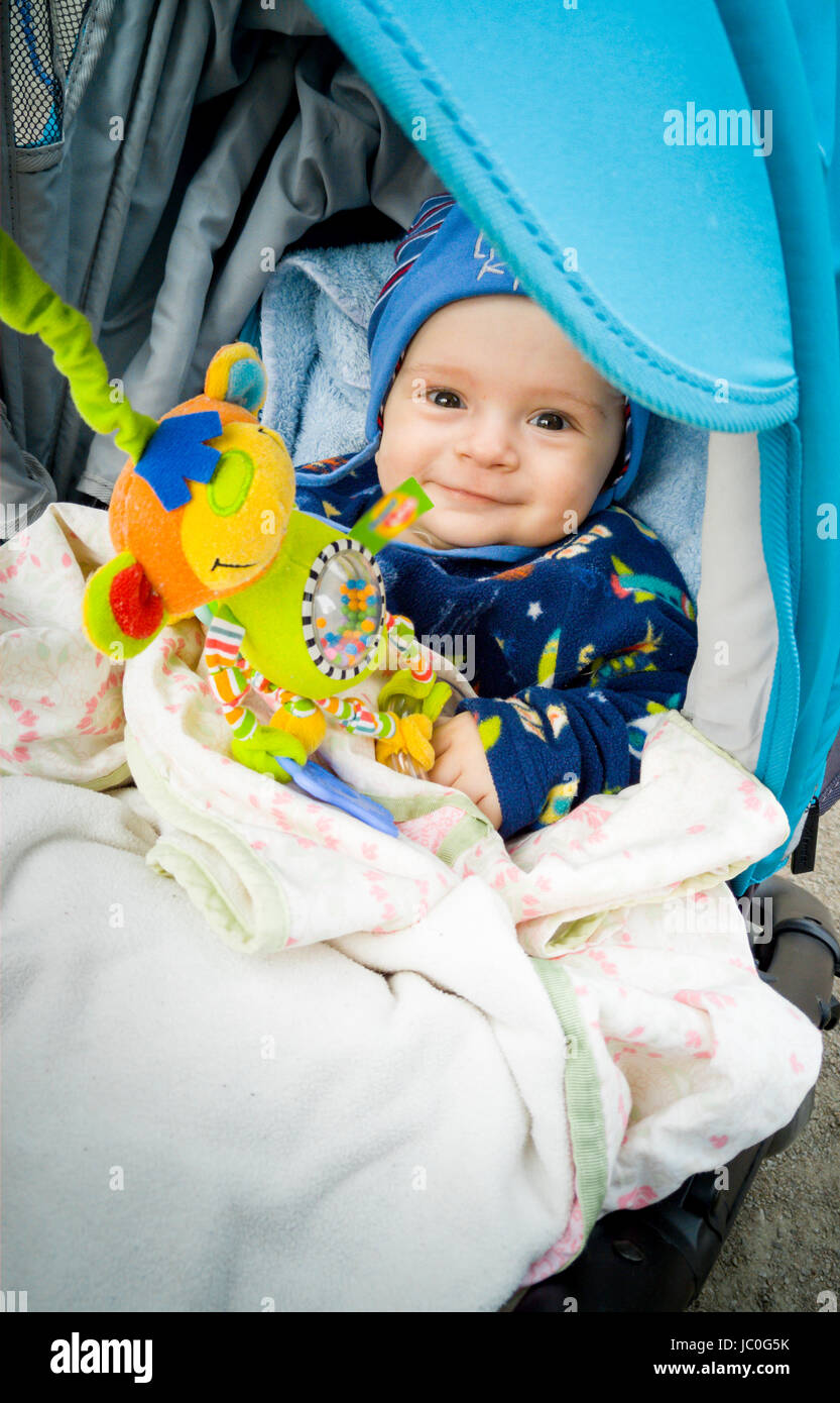 Portrait of cute smiling boy sitting in stroller with toy Stock Photo ...