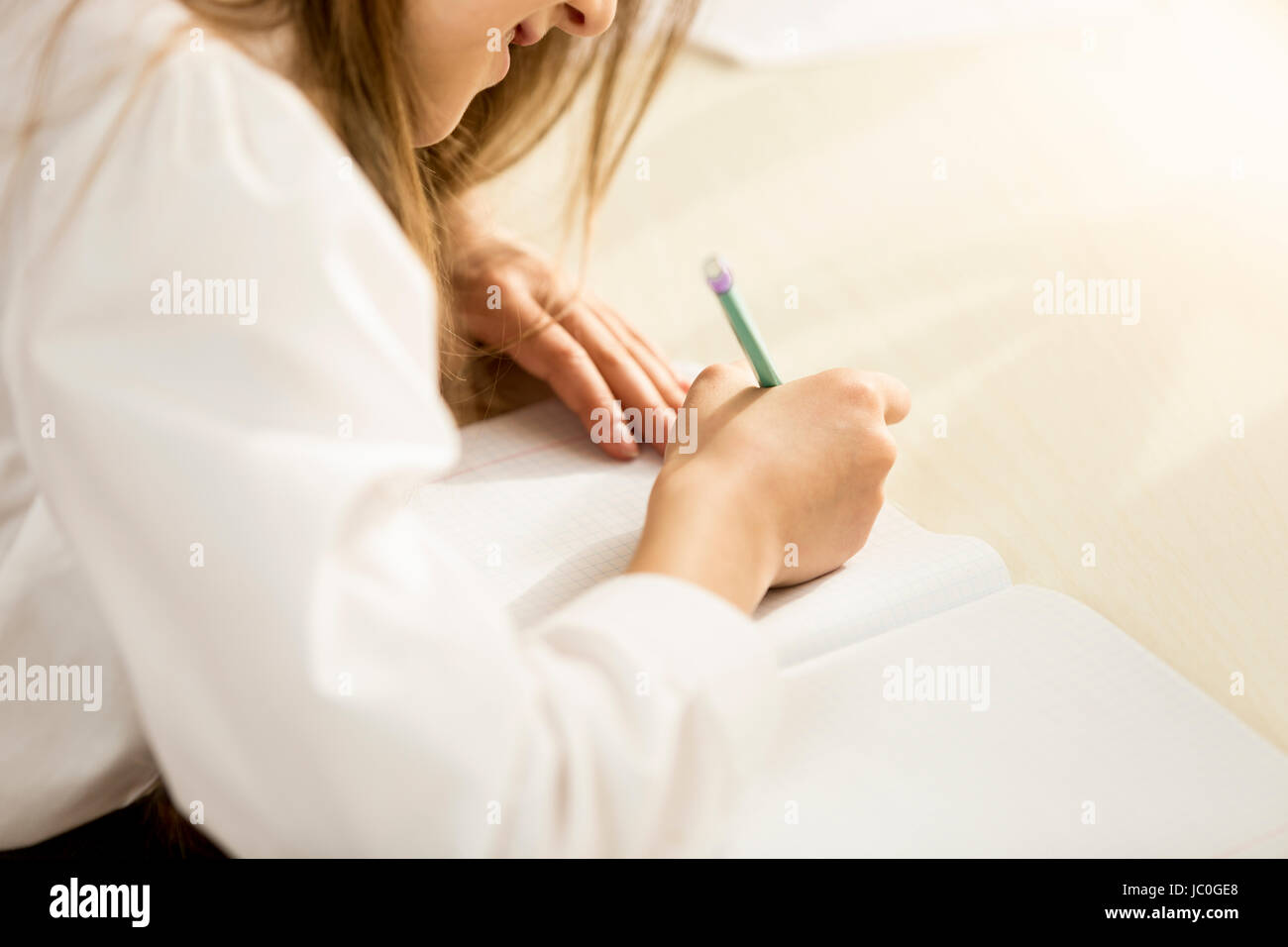 Closeup photo over shoulder of girl writing in notebook with pencil ...