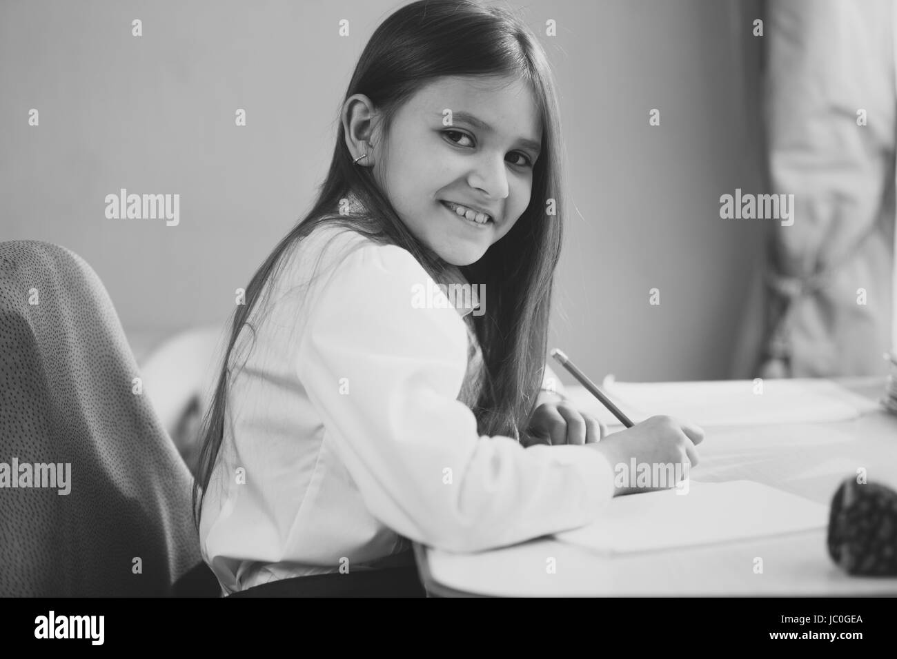 Black and white portrait of cheerful girl doing homework Stock Photo ...