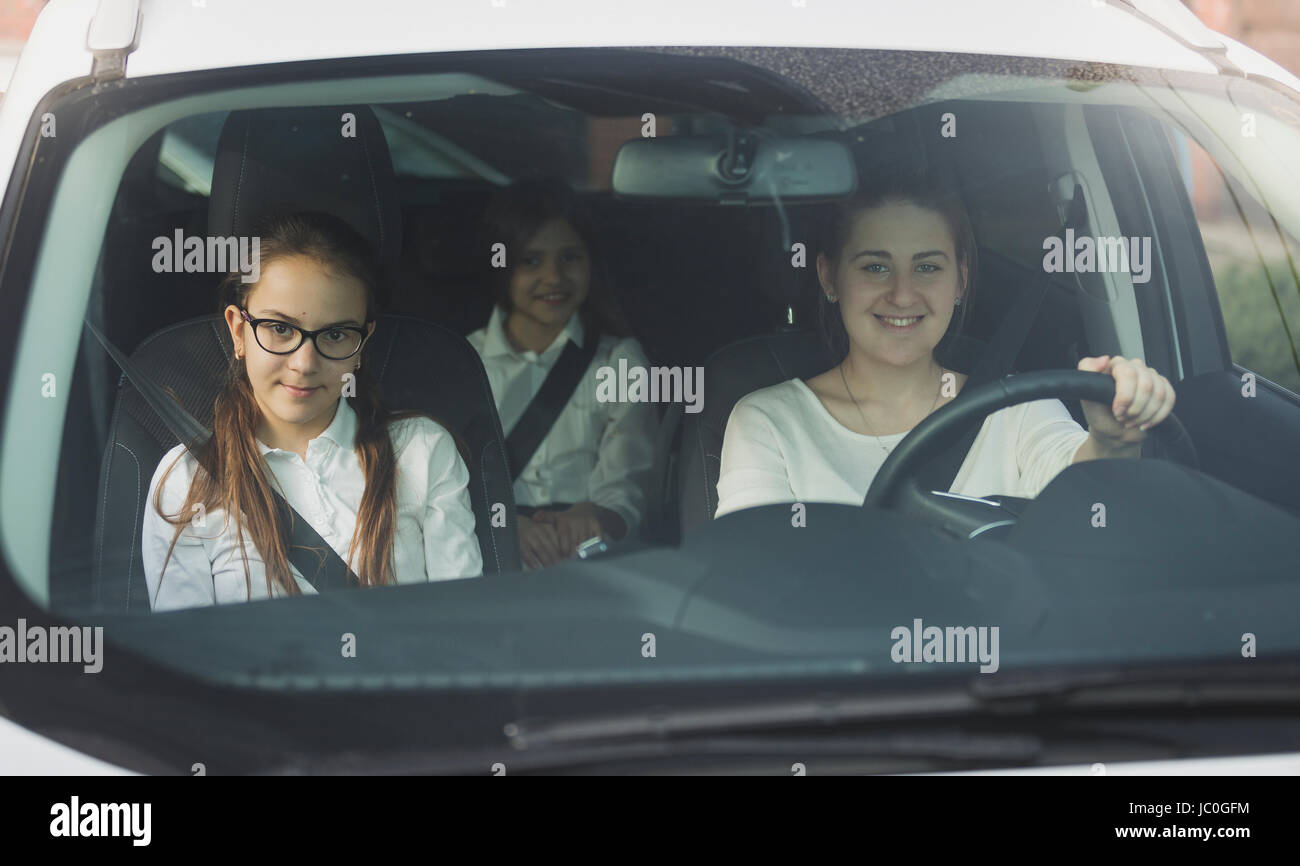 Portrait of happy mother and two daughters going home by car after ...