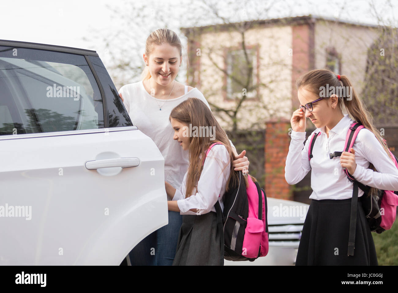 Two cute schoolgirls getting in the car to ride to school Stock Photo ...