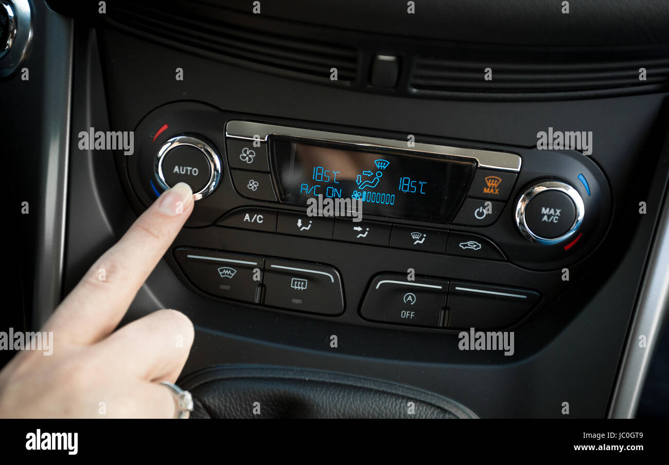 Closeup photo of woman adjusting temperature on car climate control ...