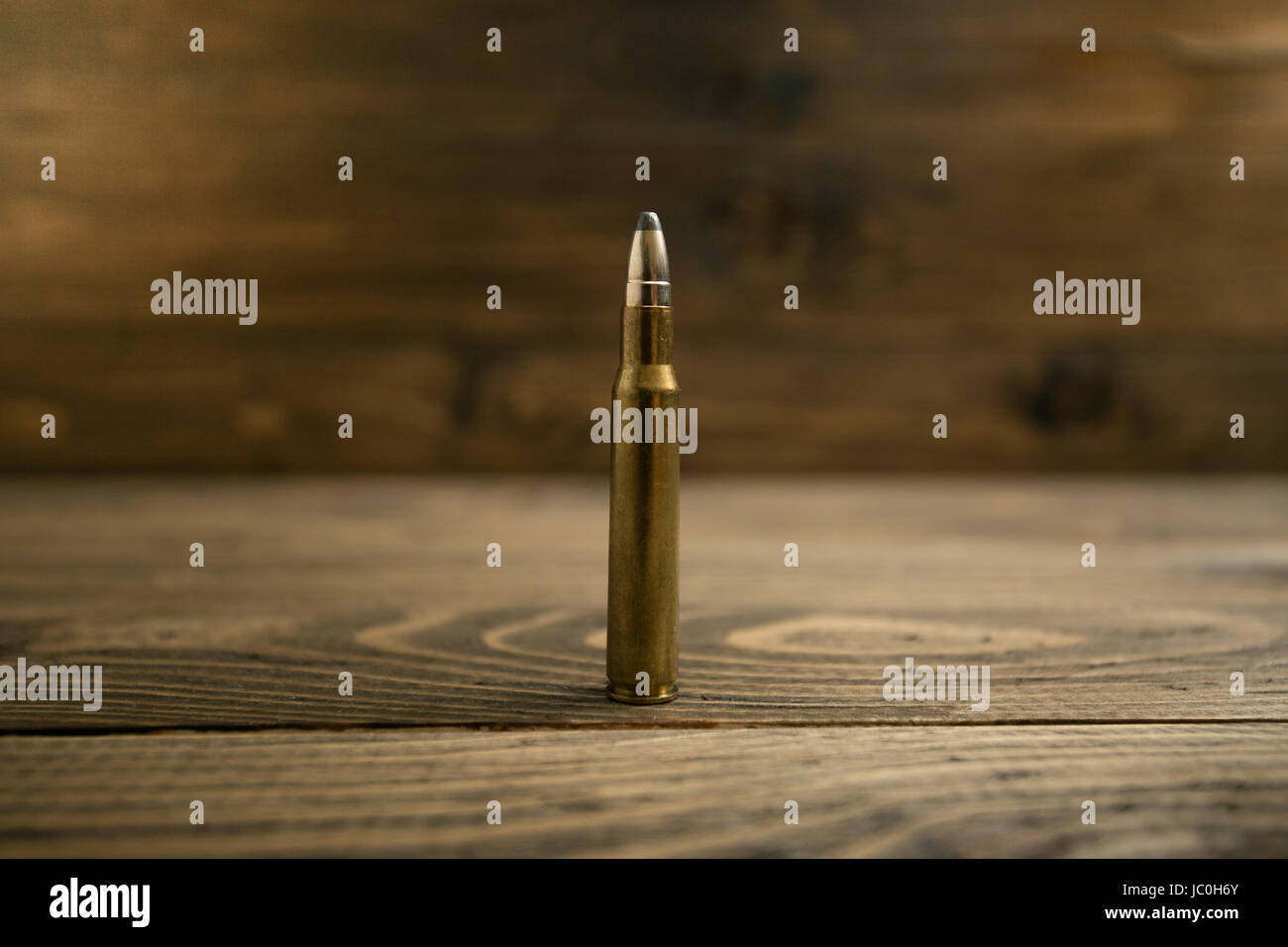 Closeup photo of riffle bullet on old wooden desk Stock Photo - Alamy
