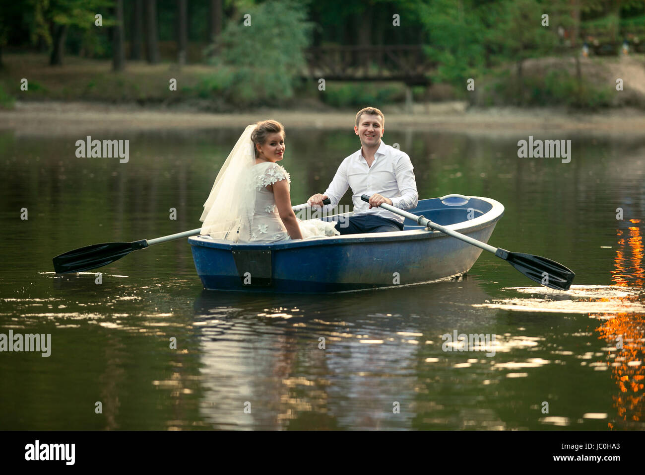 Newly married couple riding on old wooden boat on lake Stock Photo - Alamy