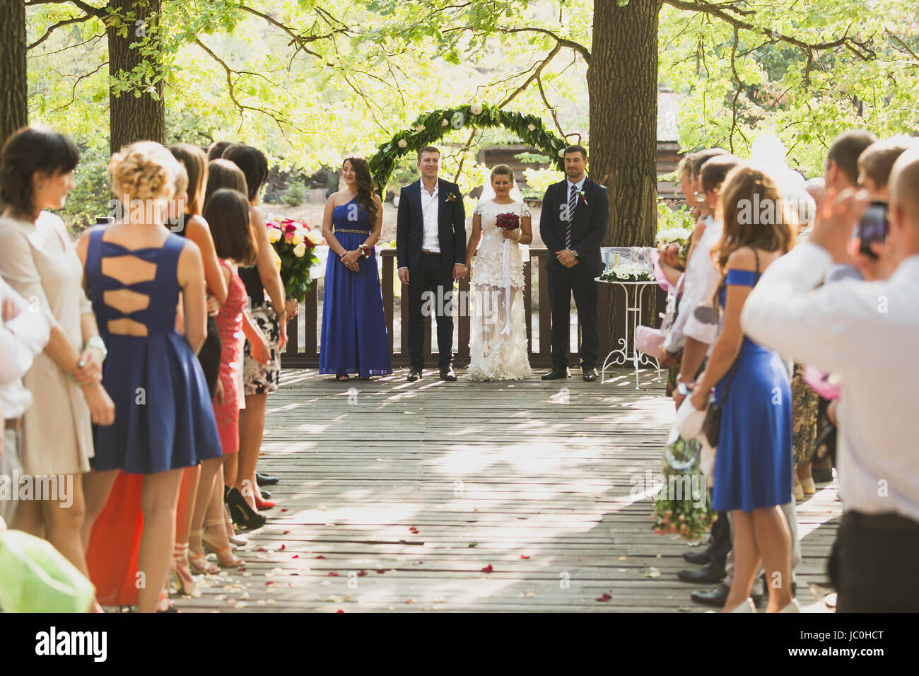 Toned photo of guests clapping to just married couple at outdoor ...
