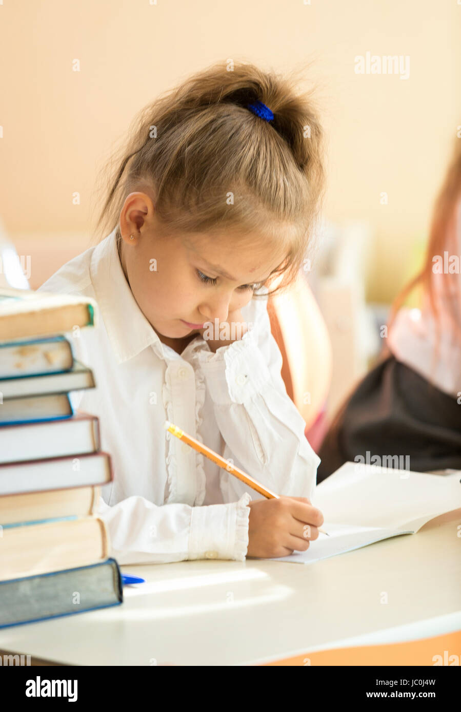 Closeup portrait of sad girl writing exercise in textbook a school ...