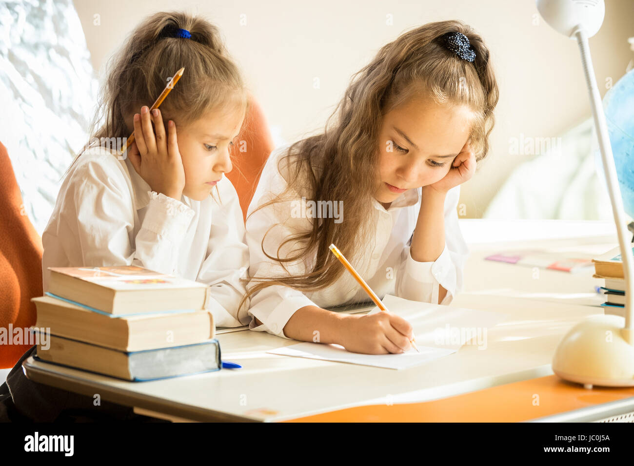 Portrait of older sister explaining homework to younger Stock Photo - Alamy