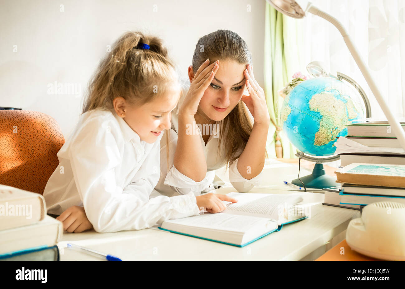 Portrait of confused mother looking at daughters complicated homework ...
