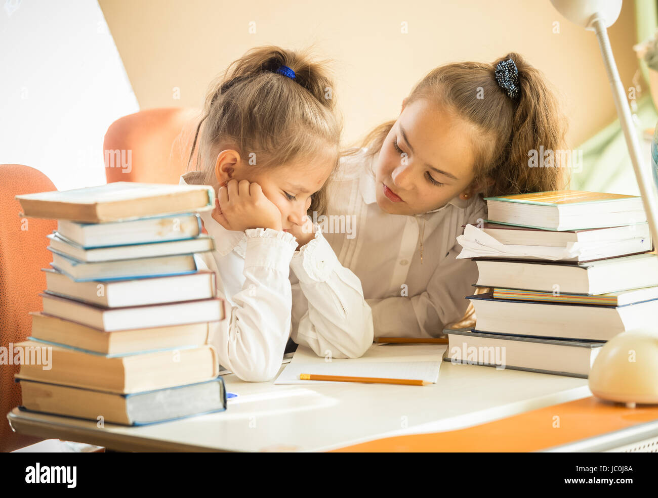 Portrait two cute girls being sad of hard homework Stock Photo - Alamy