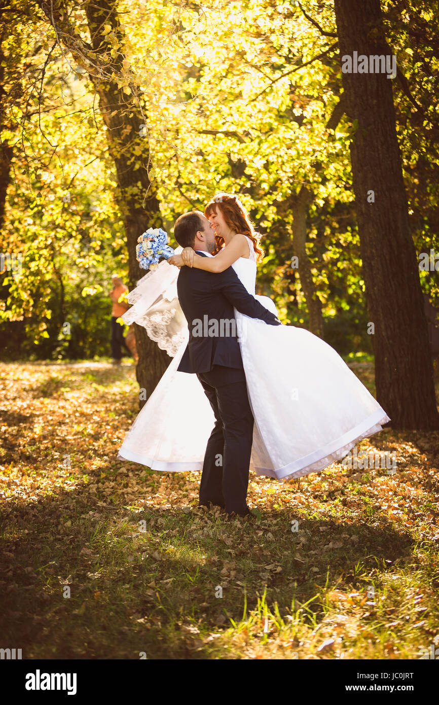 Handsome groom in suit hugging and spinning bride at autumn park Stock ...