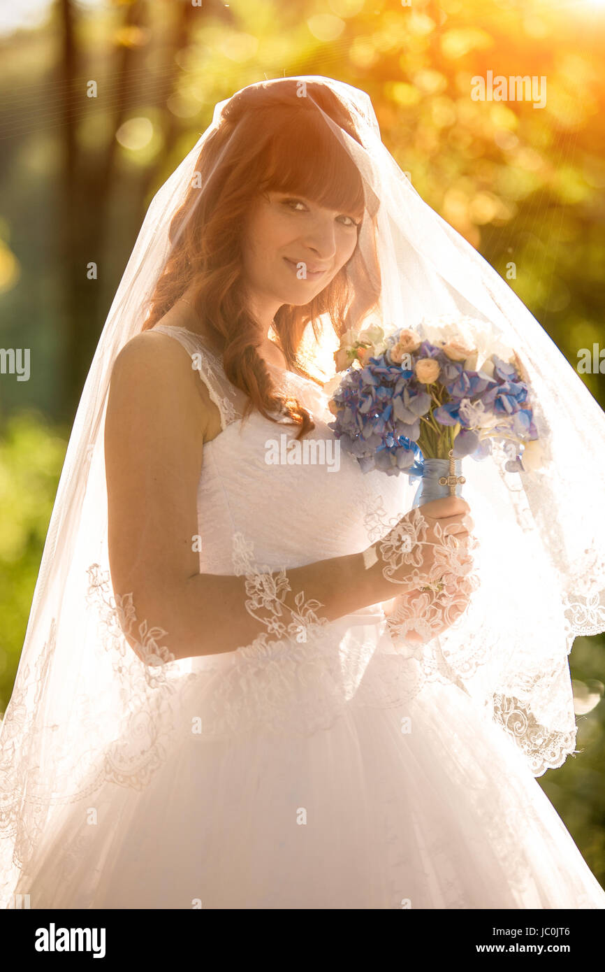 Closeup portrait of beautiful redhead bride standing in beam of light ...
