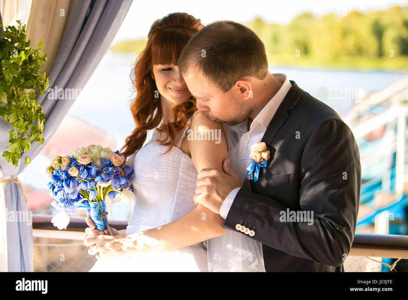 Closeup portrait of elegant groom kissing bride at shoulder at summer ...