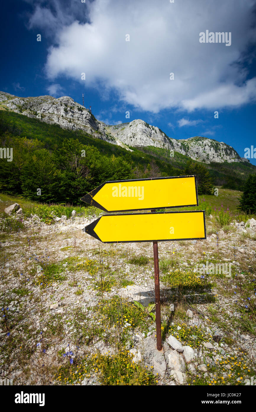 Yellow signpost standing on route to high mountain Stock Photo - Alamy
