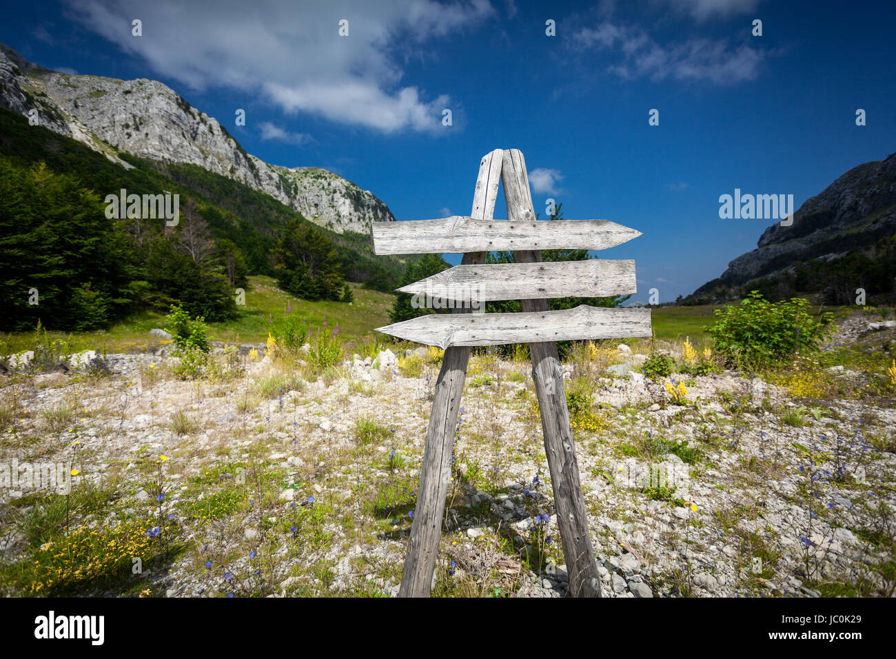 Wooden signpost with three directions on the foot of big mountain Stock ...