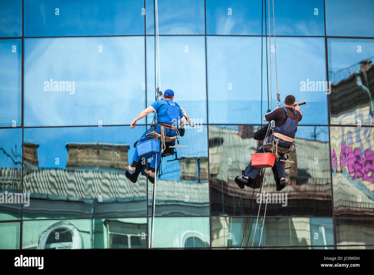 Two men cleaning window facade of skyscraper Stock Photo - Alamy
