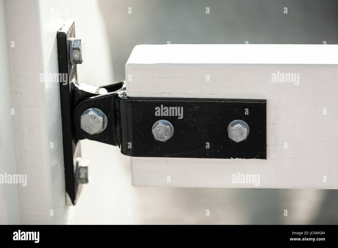 Closeup photo of metal clamp fixing two white wooden boards on bridge ...